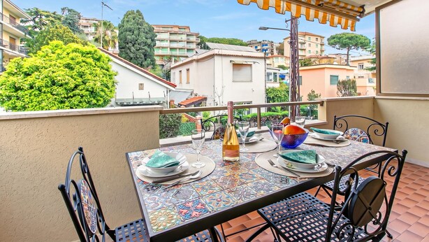 Uma varanda com mesa posta para refeições, cadeiras, uma garrafa e tigelas.