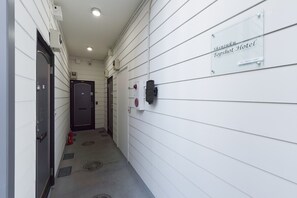 Corredor com uma placa indicando 'Shinjuku Topshot Hotel' e um alarme de incêndio na parede.