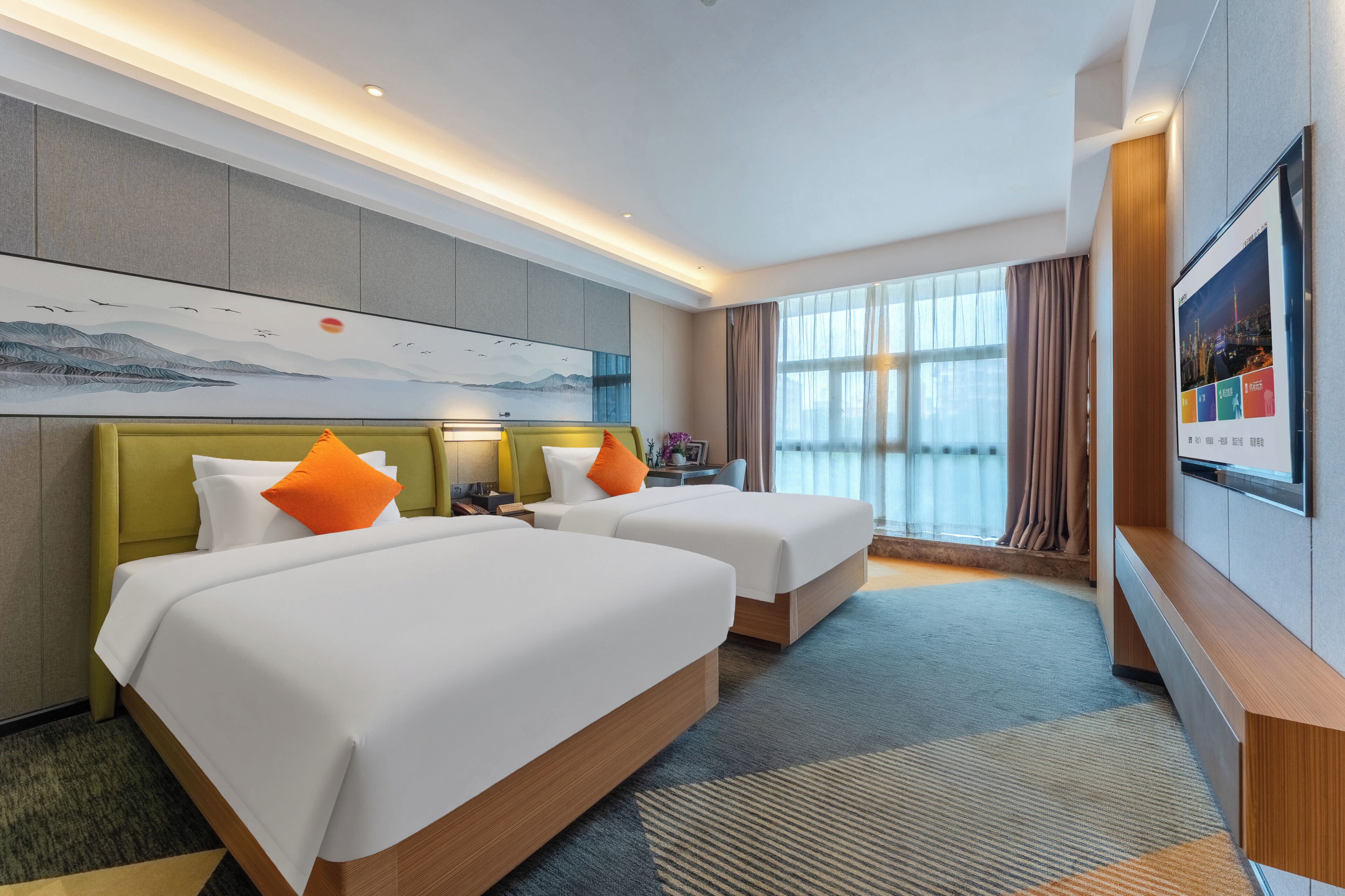 Quarto de hotel com duas camas, uma janela ampla, um quadro na parede e uma televisão de tela plana.