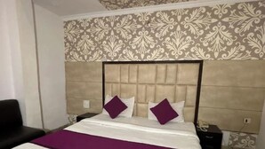 Quarto com cama, mesa de cabeceira, cadeira e papel de parede estampado.