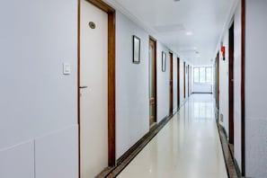 Um corredor longo e bem iluminado, com portas em ambos os lados, que dá para os quartos.