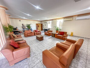 Um hall amplo com sofás de couro, uma mesa de centro e plantas em vasos.