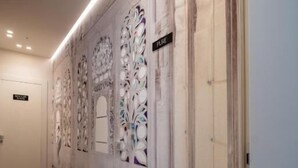 Um corredor com parede decorativa, uma porta com a inscrição 'PURE' e um letreiro indicando um 'Rooftop Bar'.
