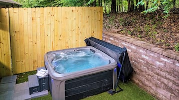 Uma banheira de hidromassagem em um quintal com cerca de madeira e parede de tijolos.