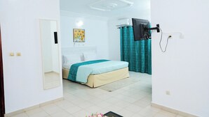 Quarto com cama, televisão na parede e janela com cortinas.