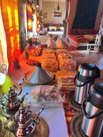 Ambiente tradicional com sofá, almofadas, mesa com alimentos e um abajur decorativo.