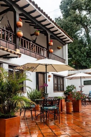 Uma área de pátio com mobiliário para áreas externas, plantas em vasos e jardineiras suspensas.