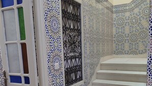 Uma escadaria com padrões de azulejos elaborados, uma porta com painéis de vidro e um quadro pendurado na parede.