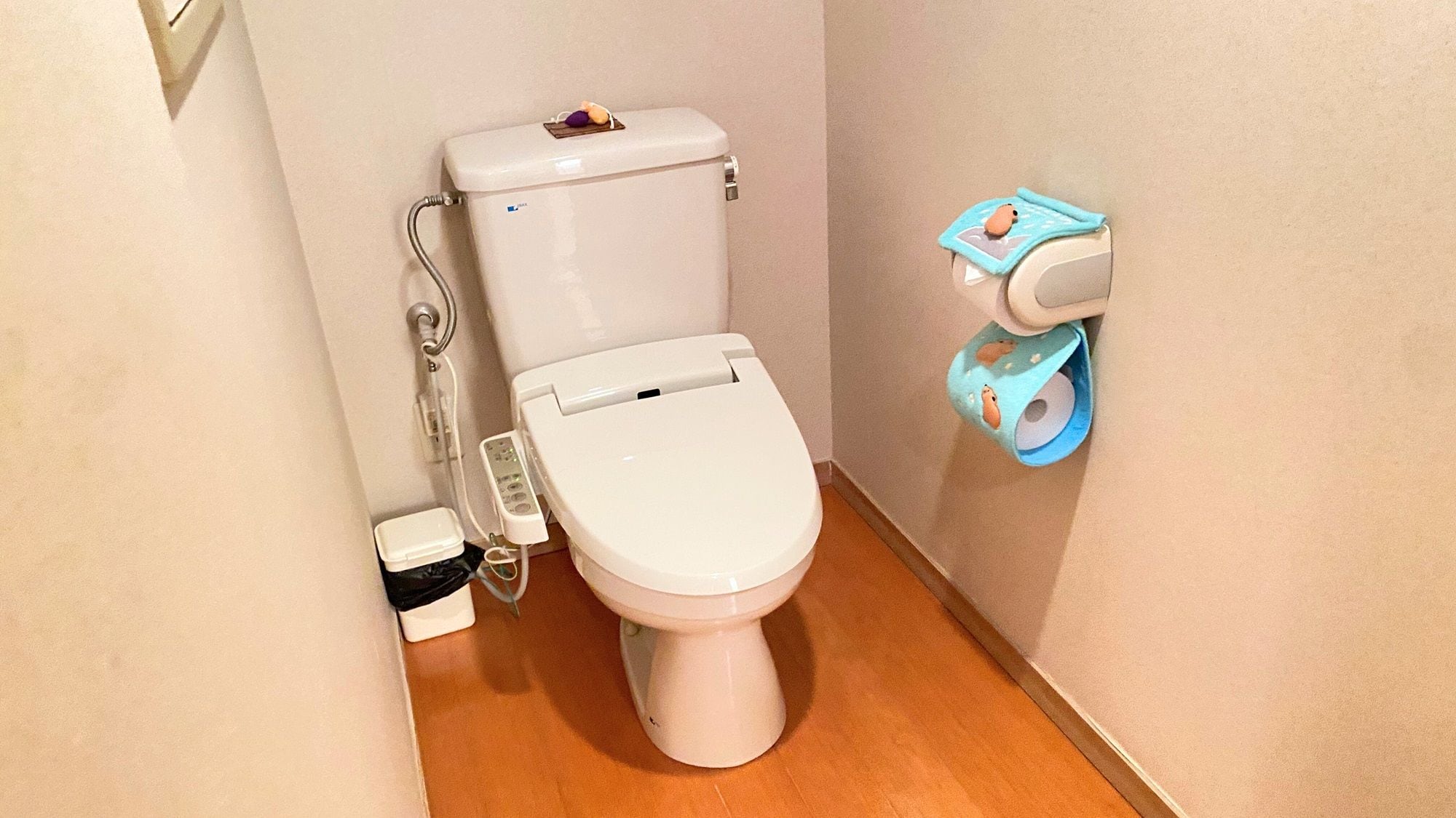 Sanitário com bidê, suporte para papel higiénico e lixeira.