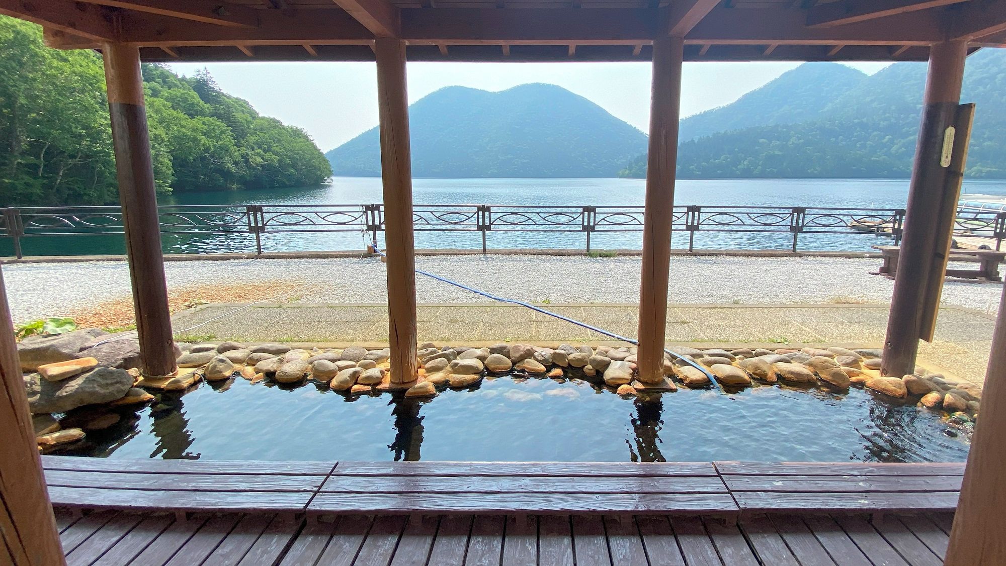 Um deck de madeira com vista para um lago e montanhas.