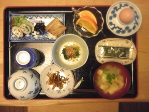 Uma bandeja com diversos pratos japoneses, incluindo sushi, sopa e legumes em conserva.