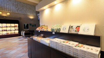 Uma área de recepção de hotel com um balcão exibindo diversos produtos embalados e uma parede com padrão decorativo.