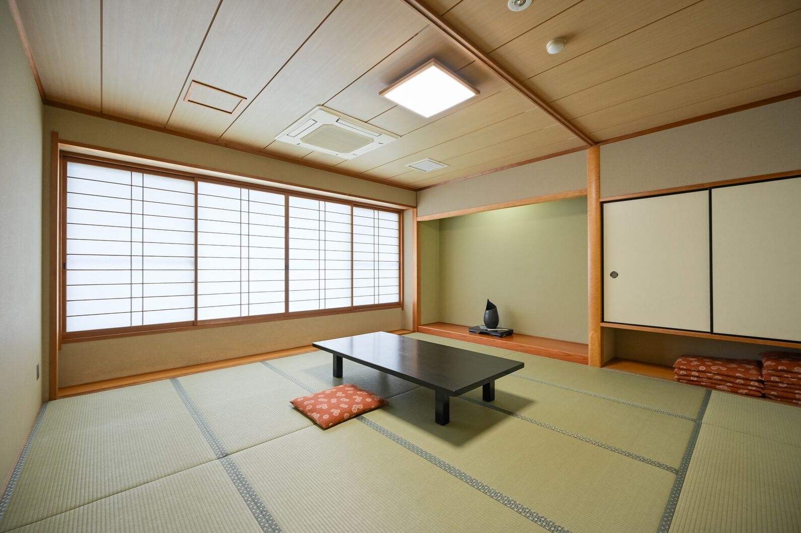 Um quarto japonês tradicional com tatames, uma mesa baixa, portas deslizantes e um armário.