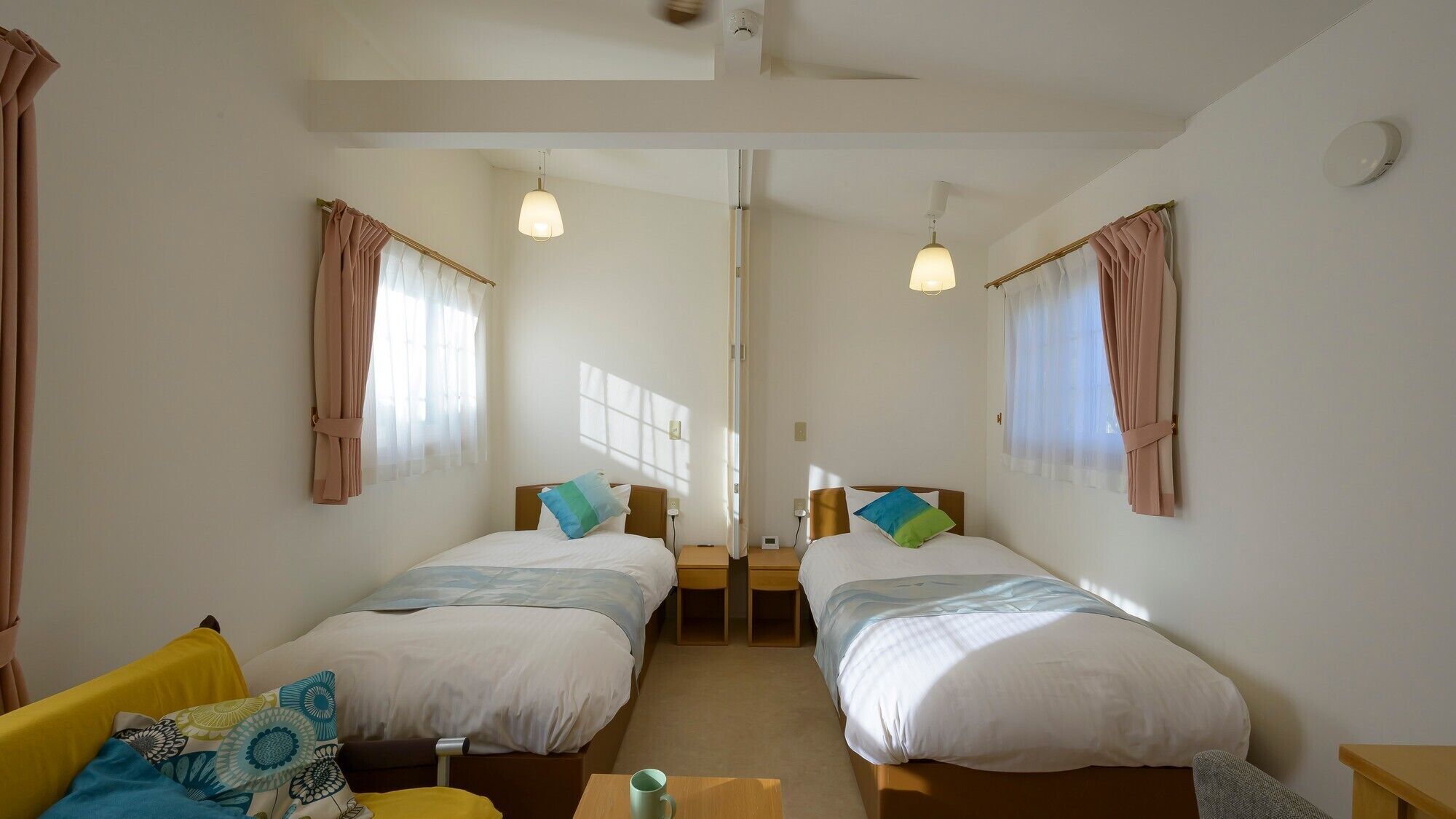 Quarto com duas camas, um sofá, uma mesa de centro e um ventilador de teto.