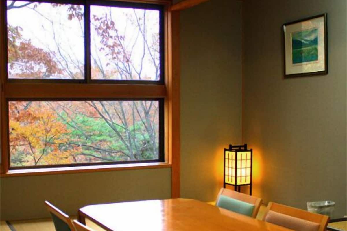 Um quarto em estilo japonês tradicional com tatames, uma mesa de madeira baixa e um painel shoji.