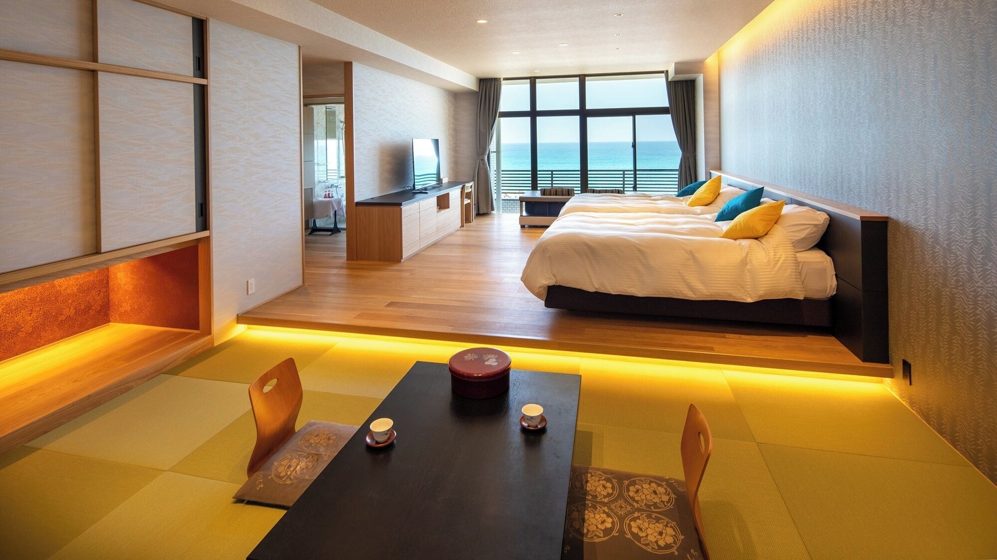 Quarto de hotel com cama, escrivaninha e vista para o oceano.