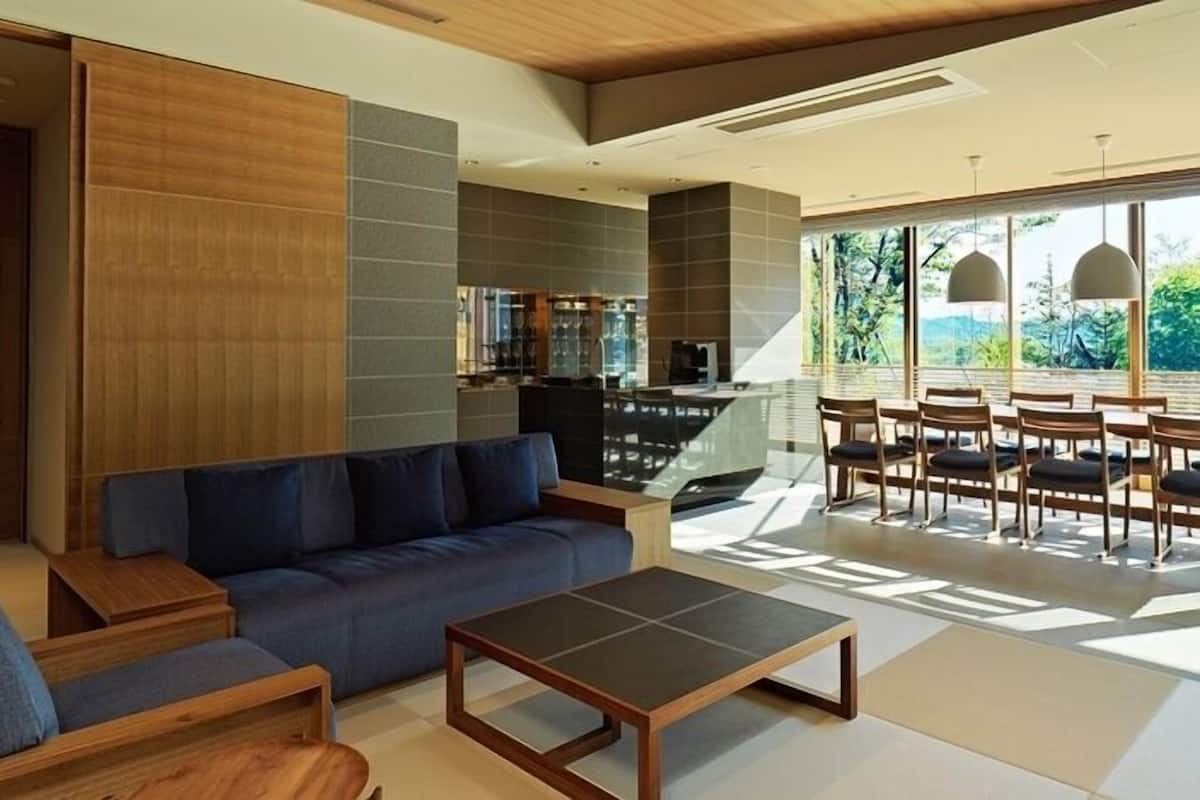 Uma sala de estar moderna com sofá, mesa de centro e área de jantar com cadeiras.
