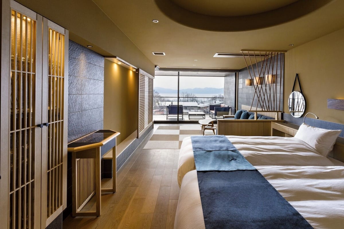 Quarto de hotel com uma cama grande, uma escrivaninha, uma cadeira e vista para a cidade.