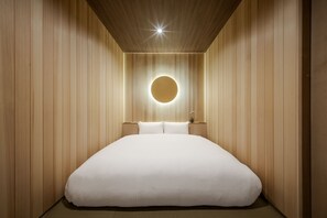 Quarto minimalista com uma cama grande, painéis de madeira e luminária circular.