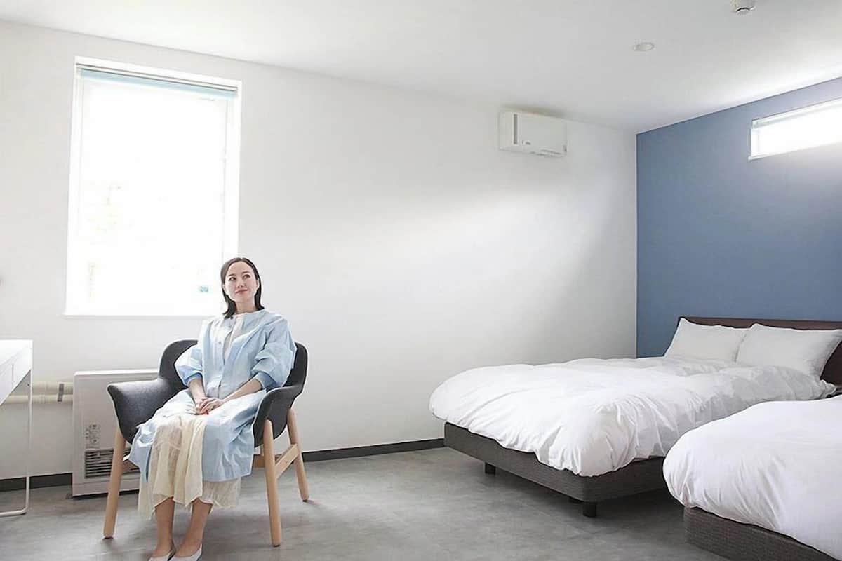 Quarto com cama, cadeira, escrivaninha e janela.