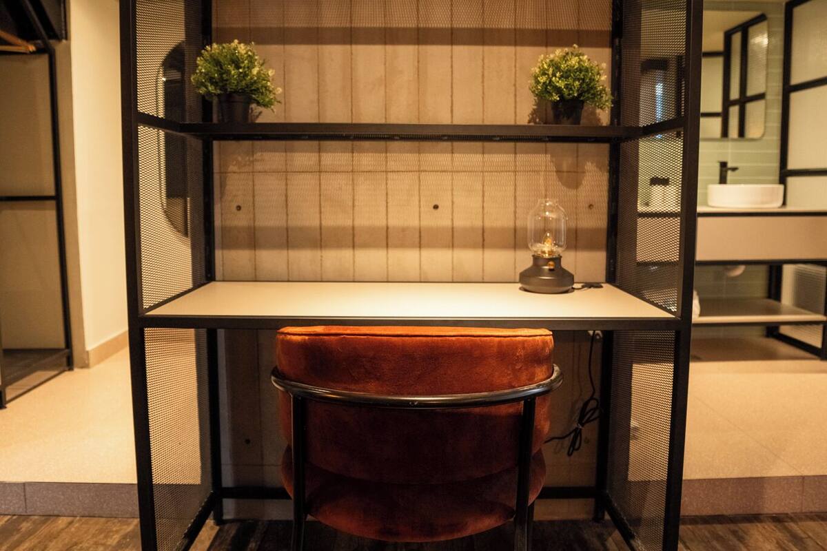 Quarto com escrivaninha, cadeira e estante com plantas.