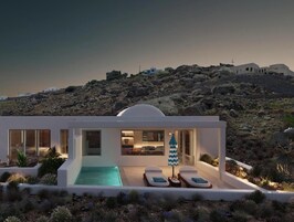 Uma villa moderna com piscina, espreguiçadeiras e vista para uma paisagem rochosa.