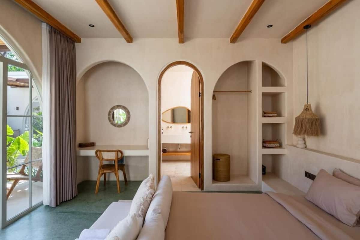 Quarto com cama, escrivaninha e vista para o exterior.