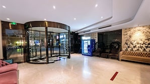 Um hall com uma porta giratória, máquina de vendas automática e área de estar.