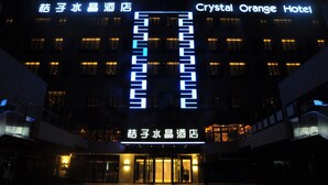 Um hotel com um destaque para o letreiro 'Crystal Orange Hotel', design arquitetônico moderno e entrada bem iluminada.