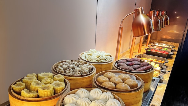 Buffet com diversos alimentos em recipientes de madeira.