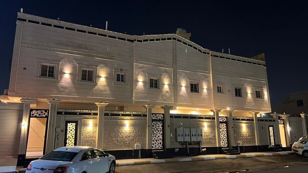 Um edifício de vários andares com entradas iluminadas e uma entrada com portão.