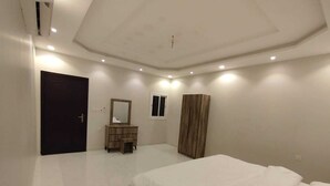 Quarto com uma cama grande, cômoda, espelho e guarda-roupa.