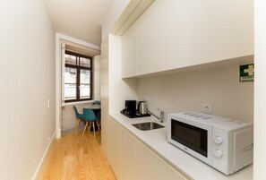 Cozinha compacta com micro-ondas, pia e janela.