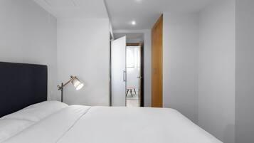 Quarto de hotel moderno com uma cama grande, uma luminária de mesa e um guarda-roupa de madeira.