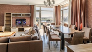 Quarto de hotel moderno com área de jantar, televisão e vista para a cidade.