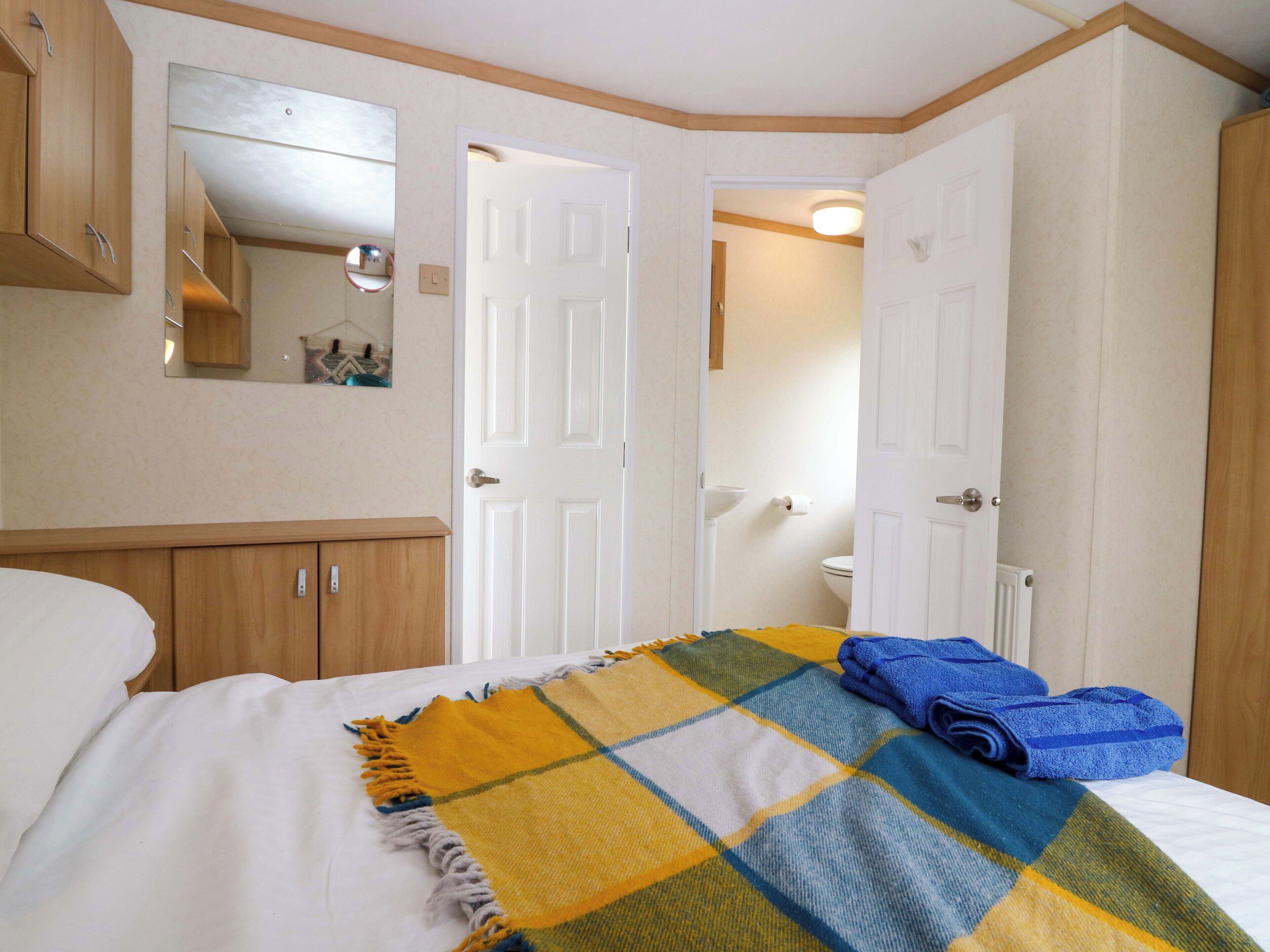 Quarto de hotel com uma cama, banheiro visível por uma porta aberta e um espelho na parede.