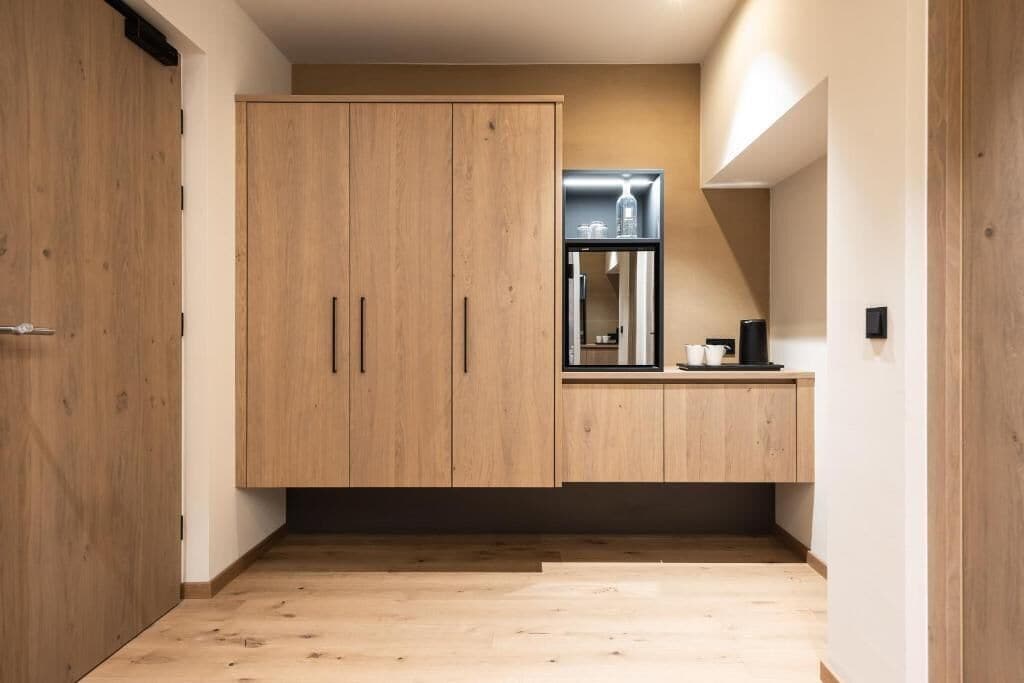 Cozinha moderna com armários de madeira, frigorífico embutido e bancada com máquina de café.