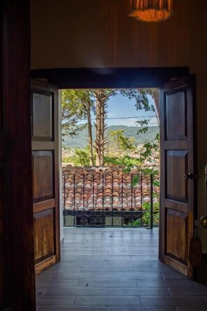 Abertura de porta que dá para uma varanda com chão de azulejos e guarda-corpo de metal.