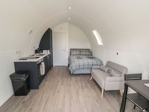 Quarto compacto com cozinha compacta, cama, sofá e mesa.