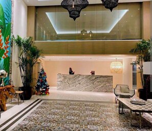 Um hall de entrada com balcão de recepção, árvore de Natal e plantas em vasos.