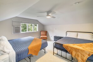 Quarto com duas camas, um ventilador de teto, janela com persianas e uma cadeira.