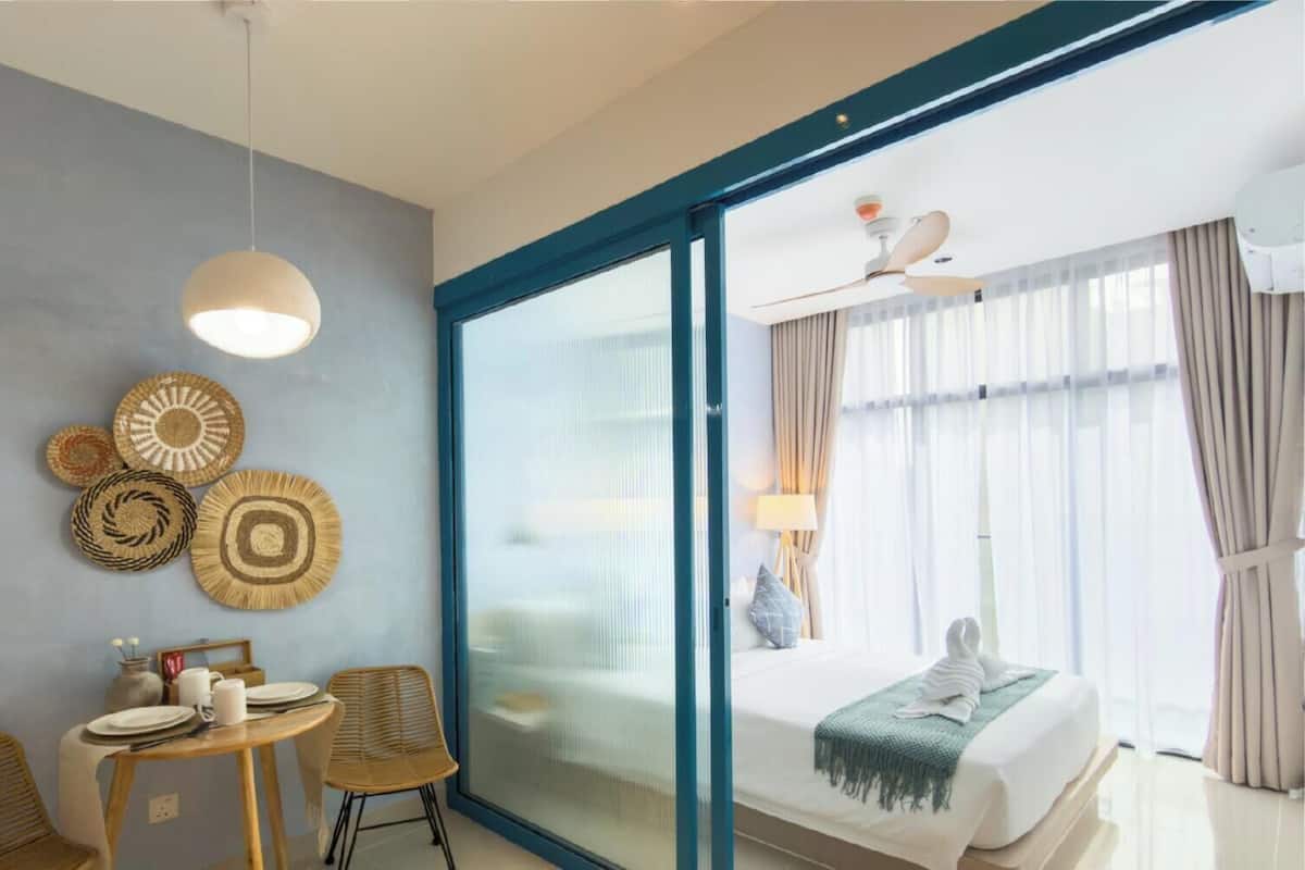 Quarto de hotel com área de refeições, cama com vista e ventilador de teto.