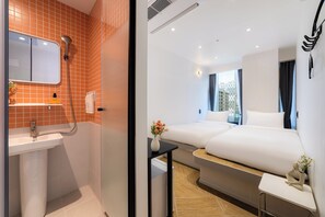 Quarto de hotel com banheiro, uma cama, mesa de cabeceira e janela com vista.