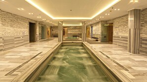 Área de spa com hidromassagem central, piso de mármore e iluminação moderna.