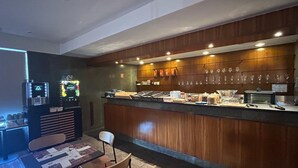 Uma área de bar com balcão, cadeiras e uma exposição de copos.
