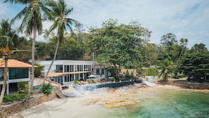 Uma propriedade à beira-mar com uma casa moderna, piscina e área de praia.