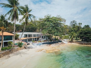 Uma propriedade à beira-mar com uma casa moderna, piscina e área de praia.