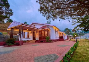 Um edifício de dois andares com telhado de telhas, varanda coberta e calçada pavimentada.