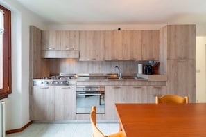 Uma cozinha moderna com armários de madeira, eletrodomésticos de aço inoxidável e uma mesa de jantar de madeira.
