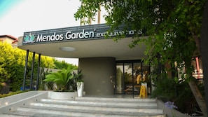 Entrada de um prédio moderno com uma placa indicando 'Mendos Garden'.